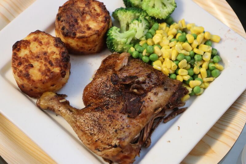 Sous vide crispy duck legs served with cheesey potatoes peas and ...
